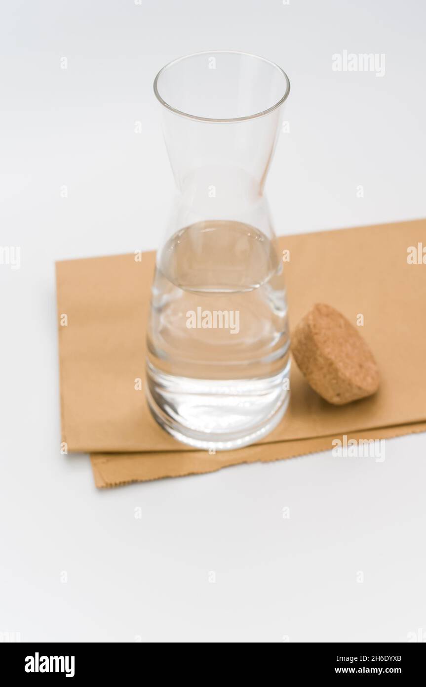 glass carafe with fresh water and cork lid on a white and brown paper ...