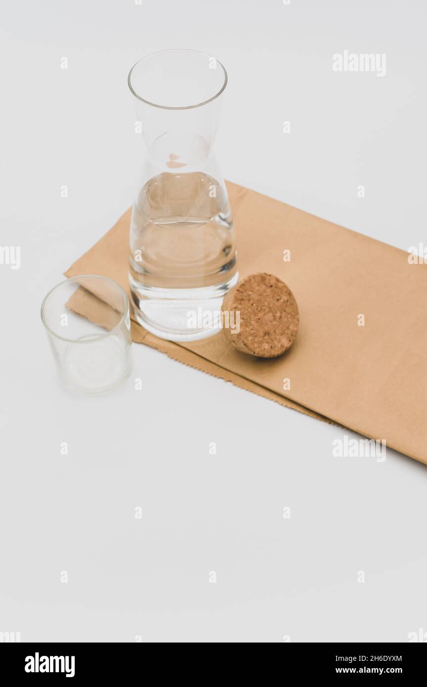 glass carafe with fresh water and cork lid on a white and brown paper ...