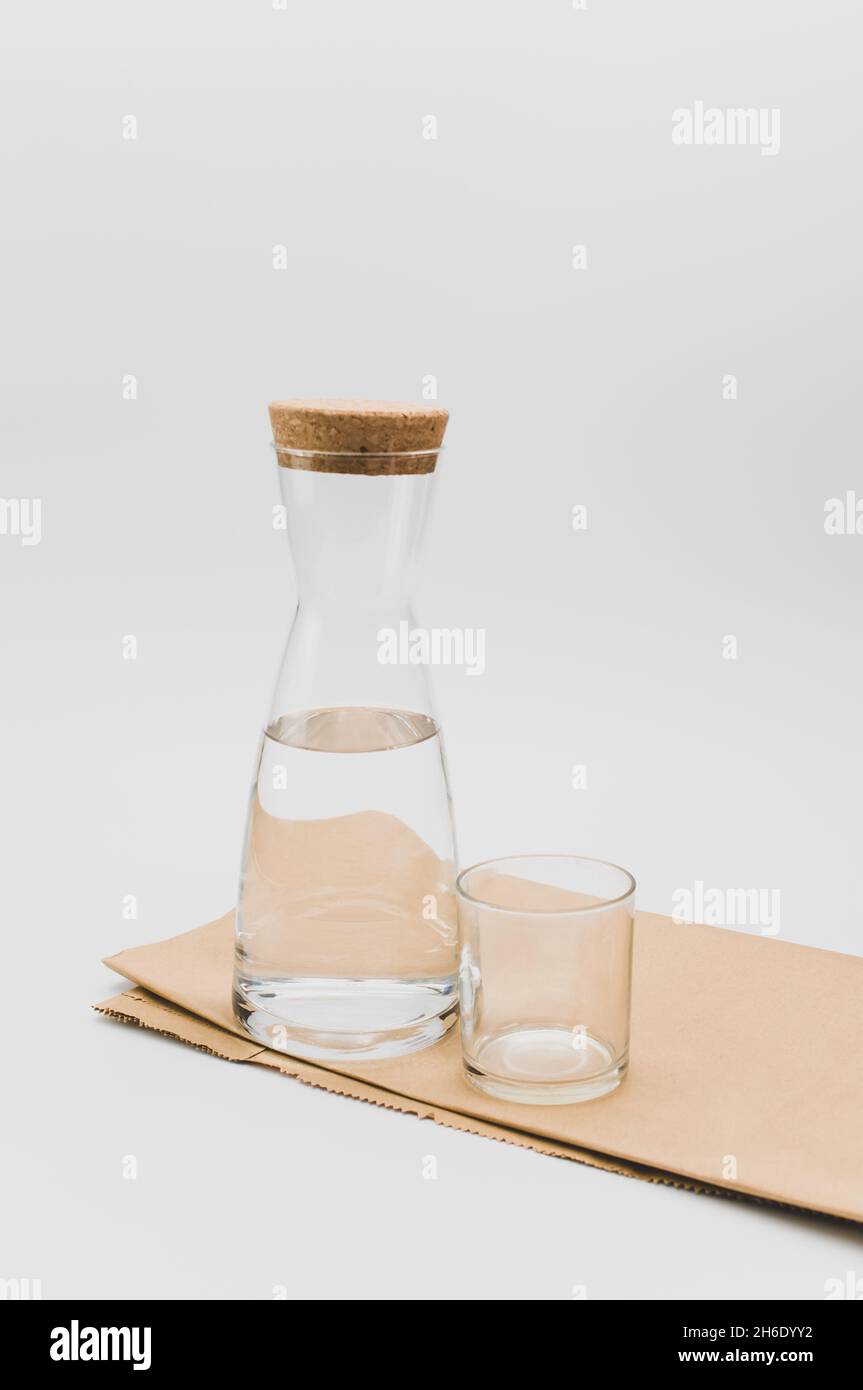 glass carafe with fresh water and cork lid on a folded paper bag white ...