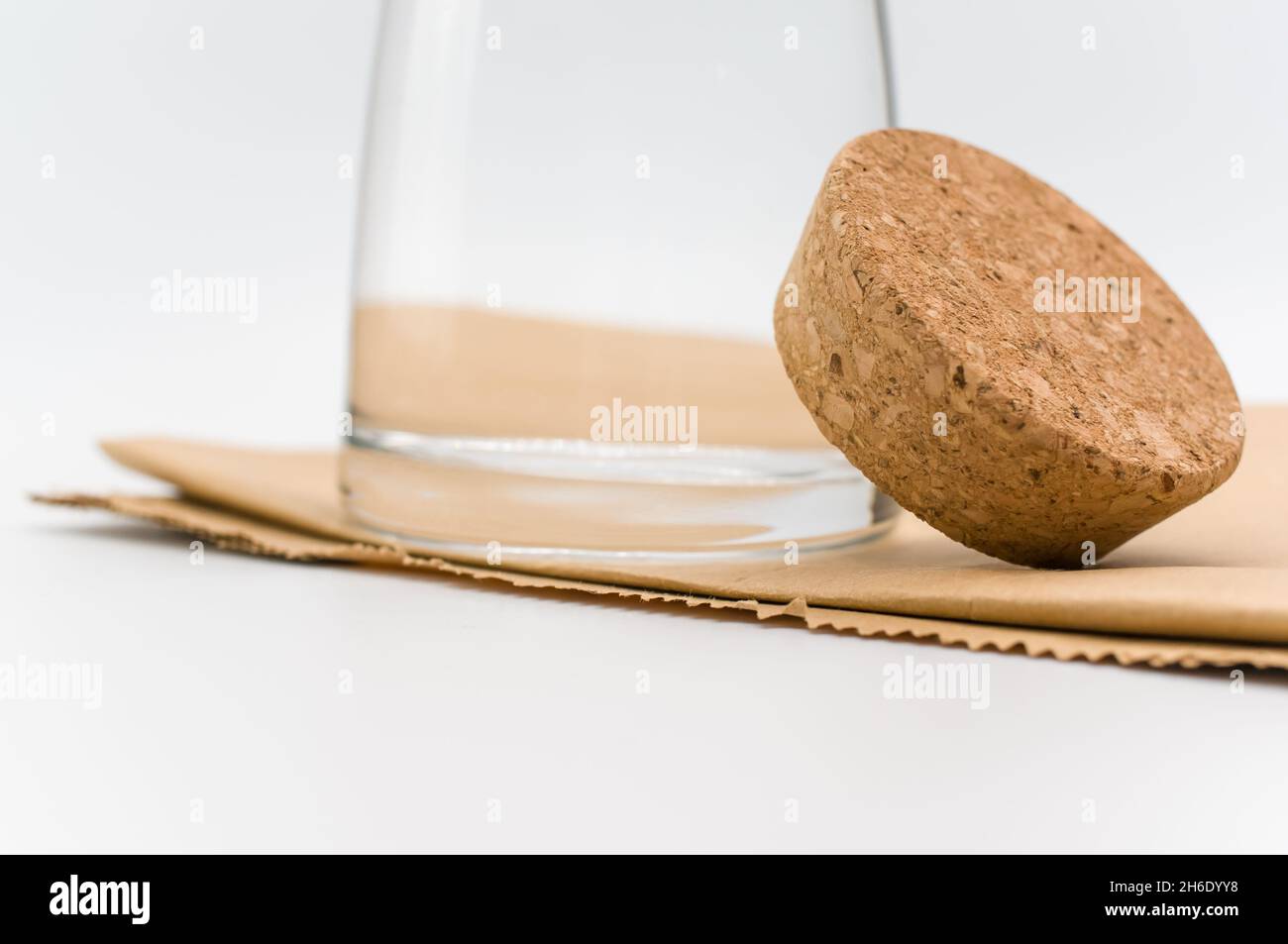 glass carafe with fresh water and cork lid on a white and brown paper ...