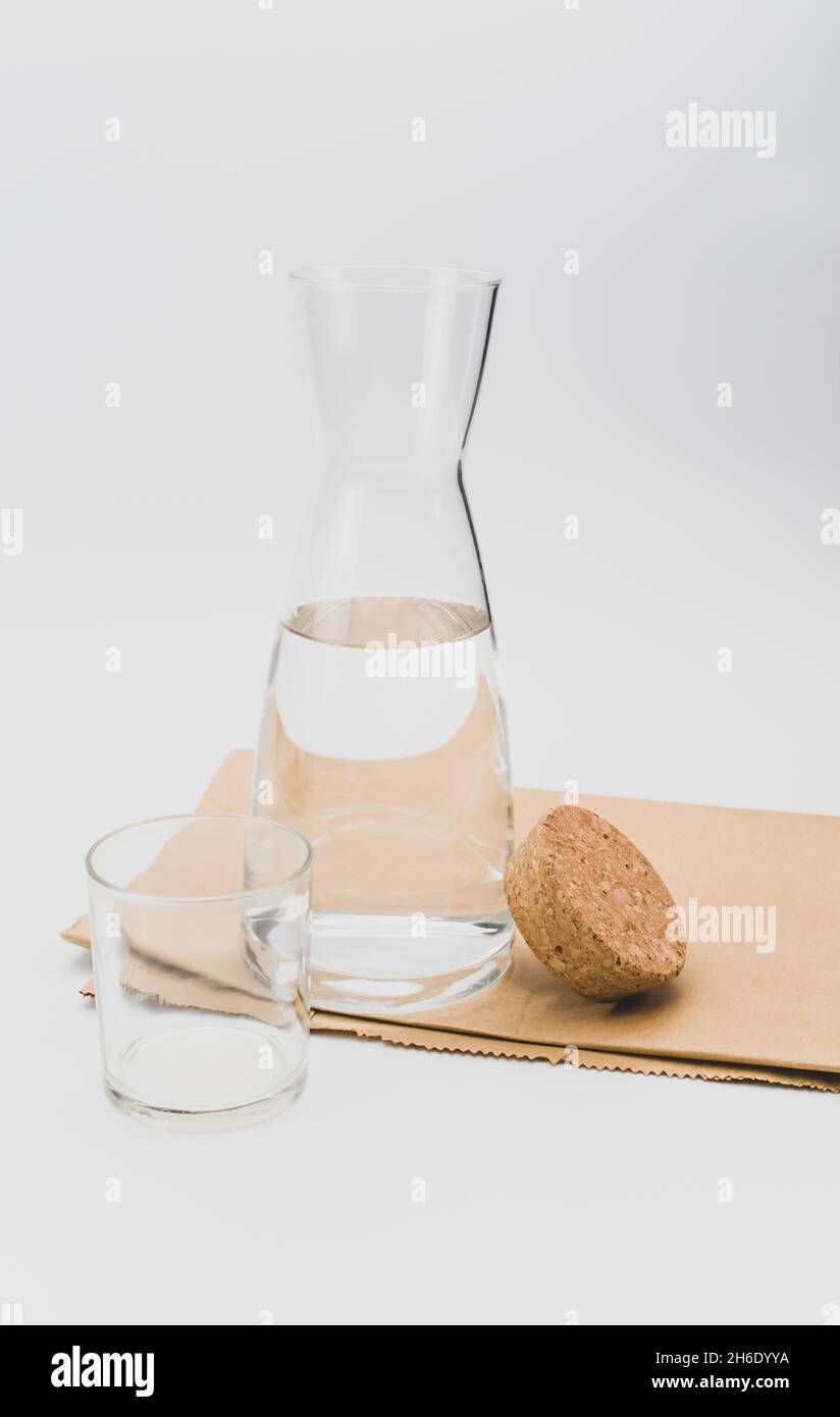 glass carafe with fresh water and cork lid on a white and brown paper ...