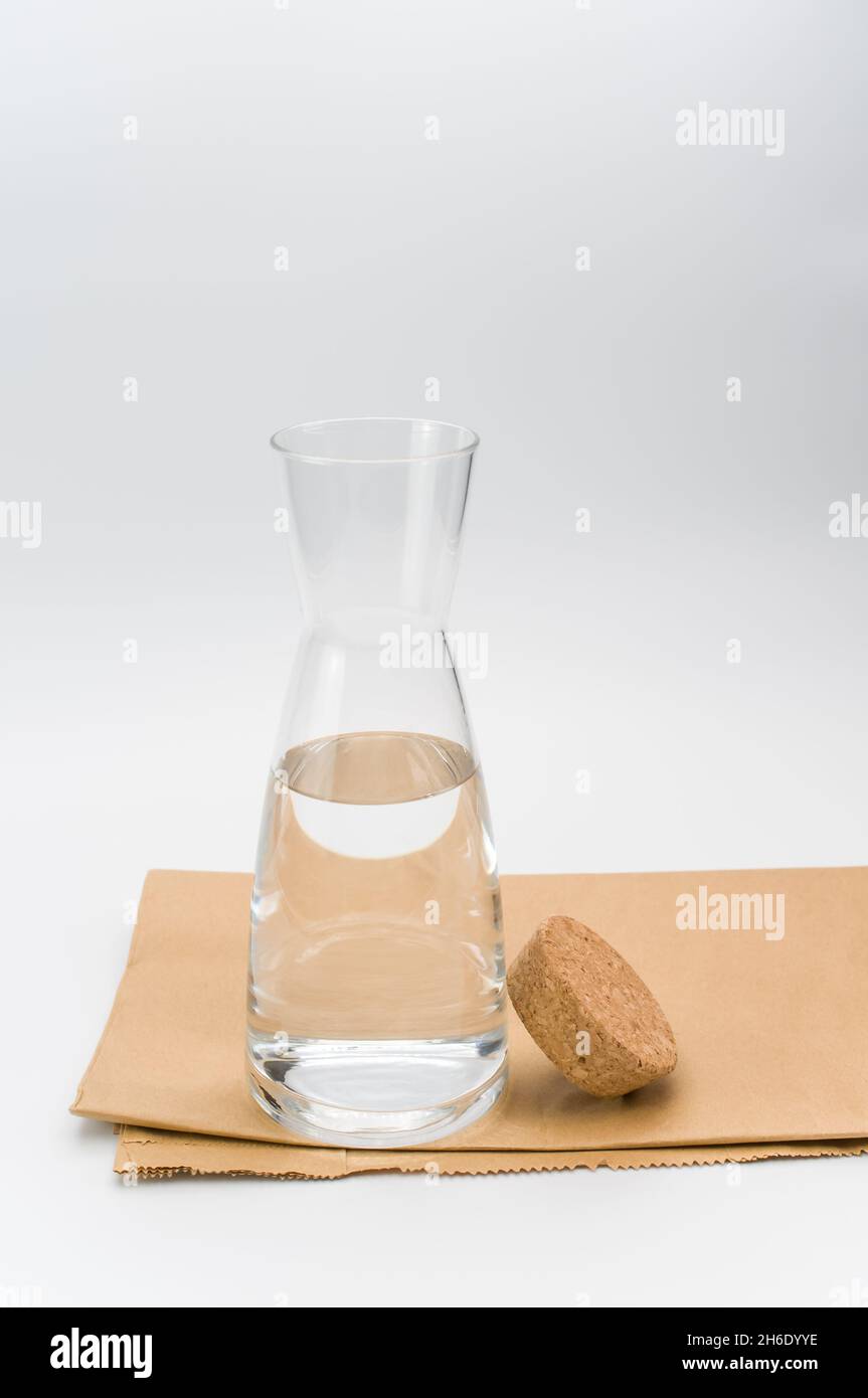 glass carafe with fresh water and cork lid on a white and brown paper ...