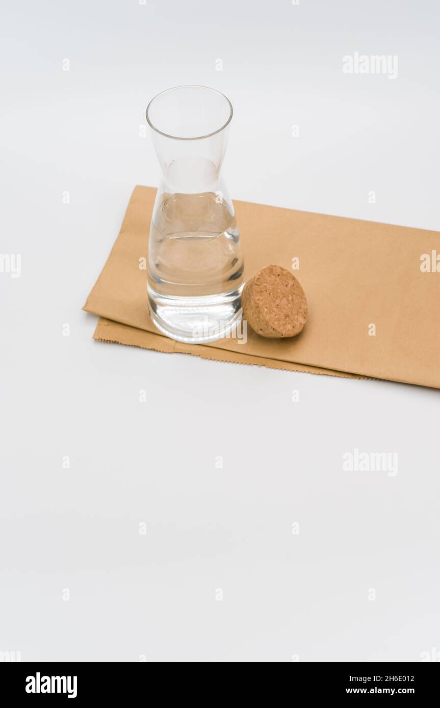 glass carafe with fresh water and cork lid on a white and brown paper ...