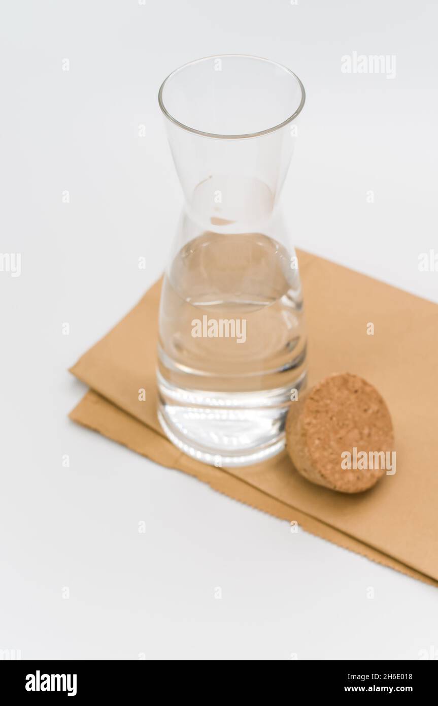 glass carafe with fresh water and cork lid on a white and brown paper ...