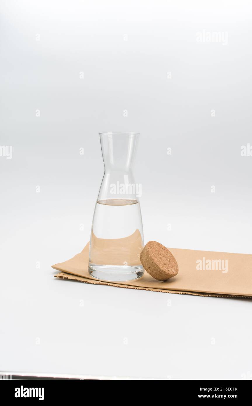 glass carafe with fresh water and cork lid on a white and brown paper ...
