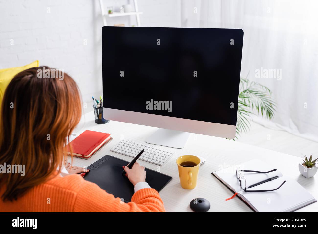 back view of designer working on graphic tablet near computer monitor ...