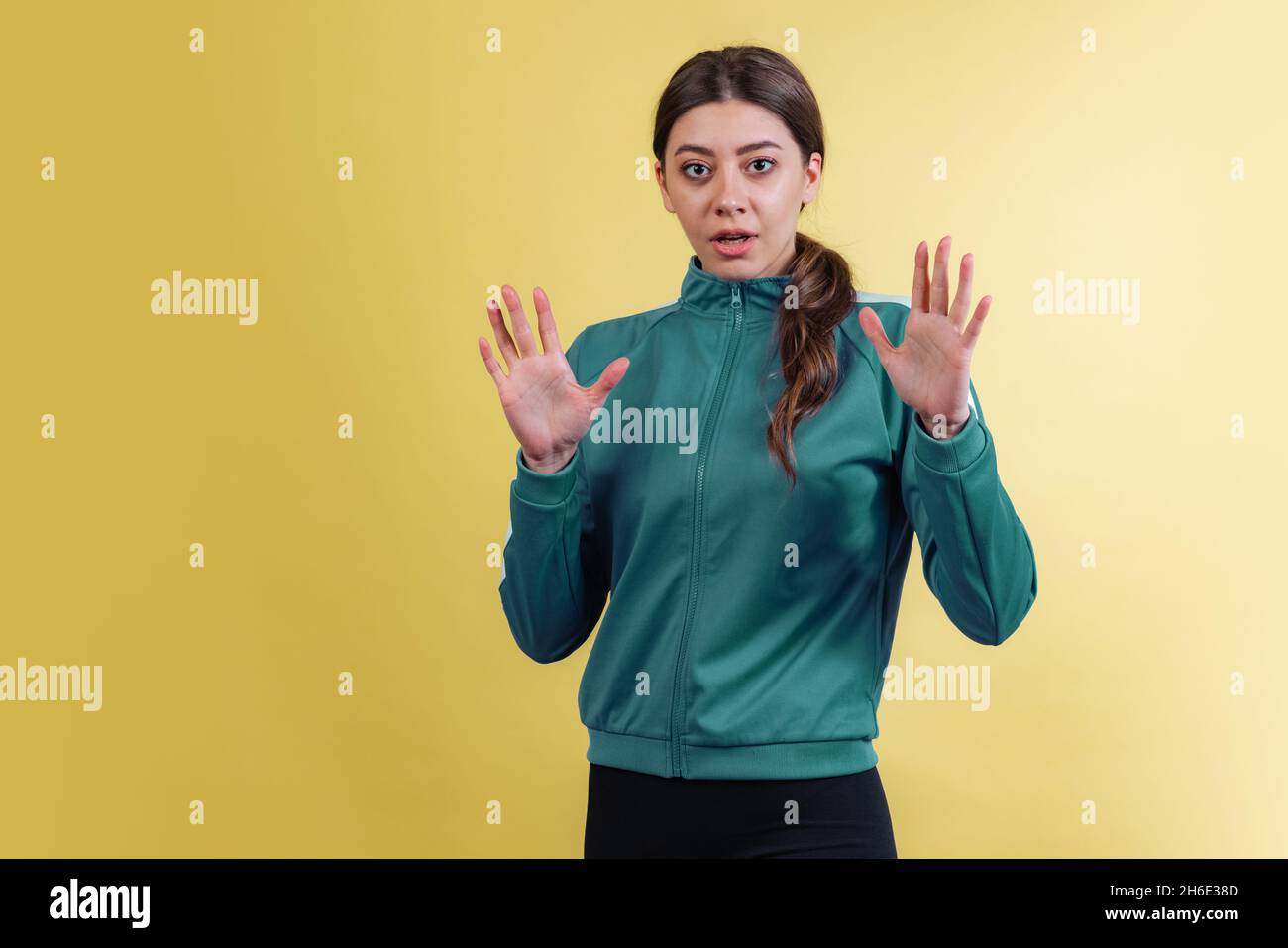 Portrait of young scared girl in green tracksuit posing isolated on ...