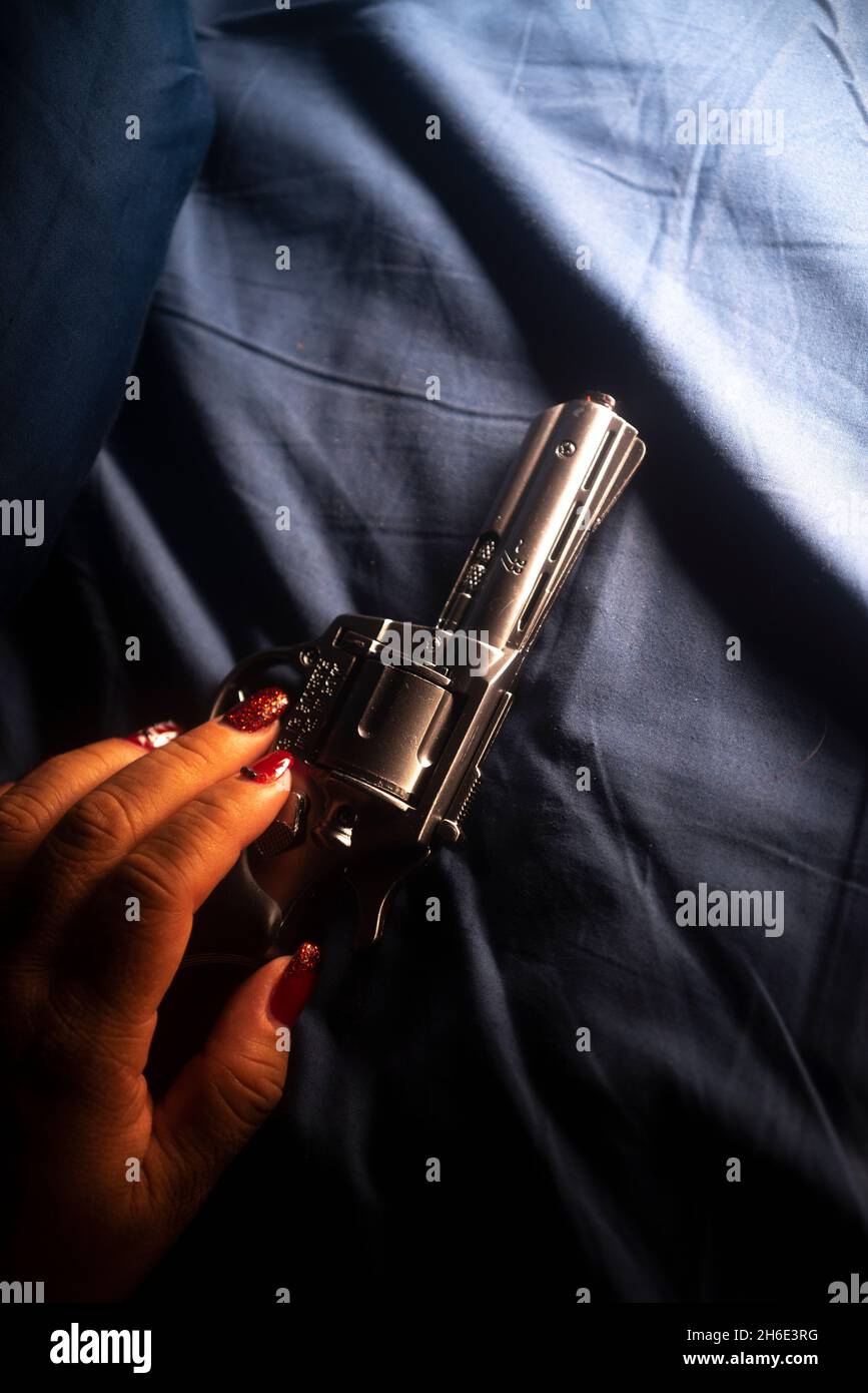 Lady spy detective with painted red nail varnish holding pistol gun at ...