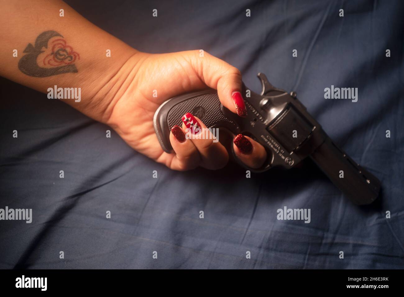 Lady spy detective with painted red nail varnish holding pistol gun at ...