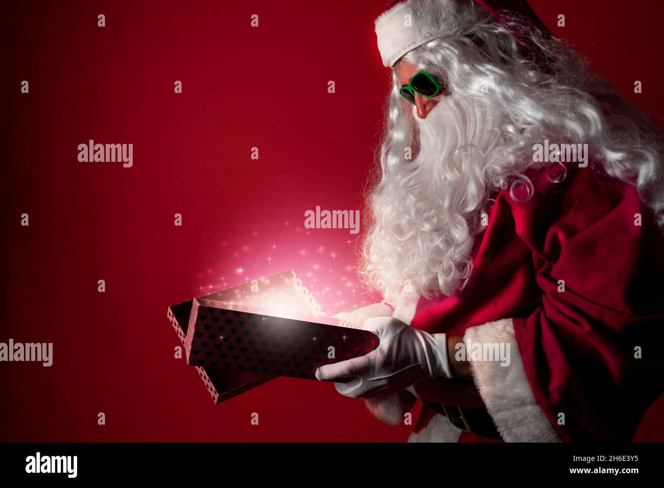 Santa Claus opening a gift box full of Christmas magic dust on a red ...