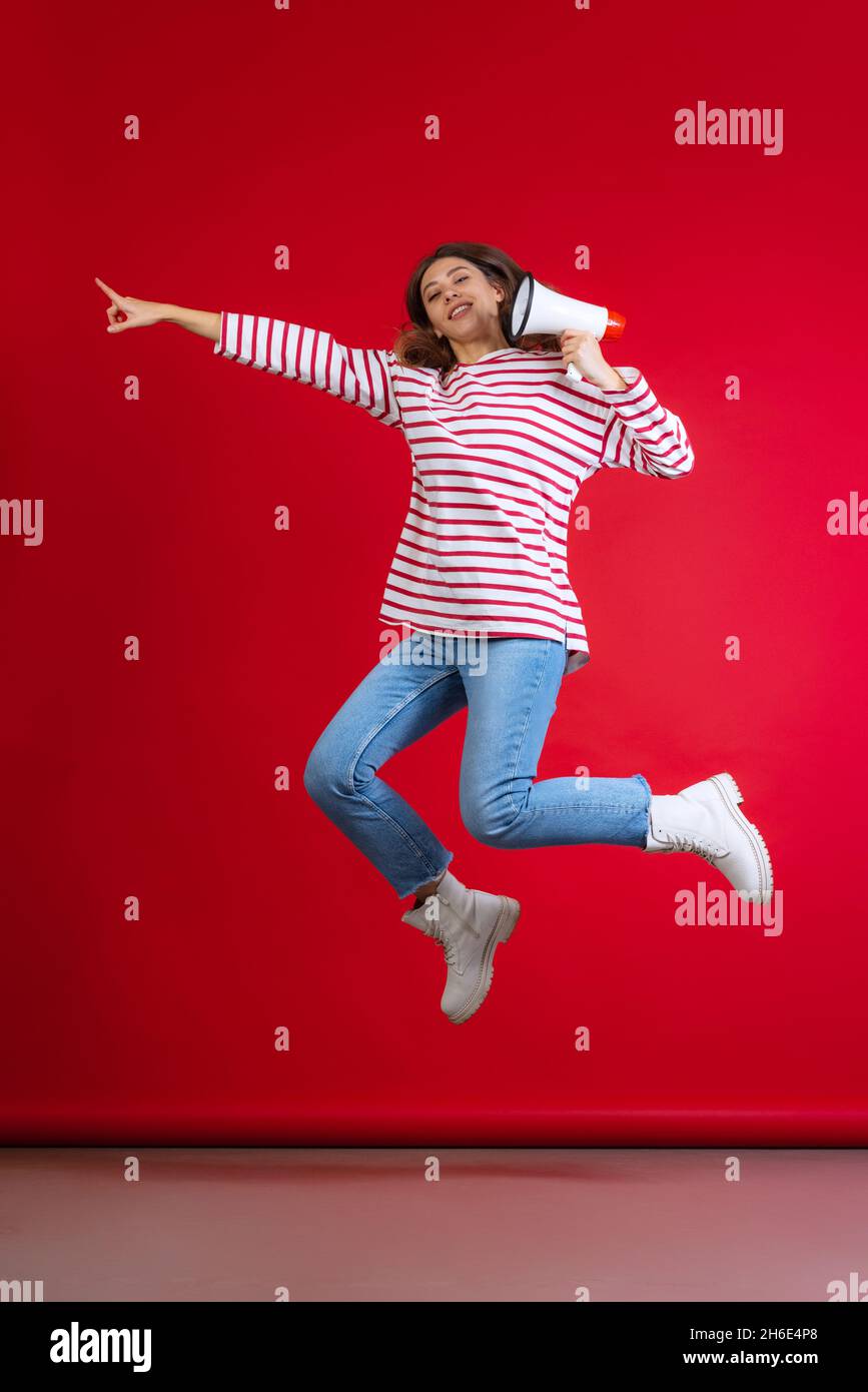 Emotional young beautiful girl in sweater and jeans jumping isolated on ...