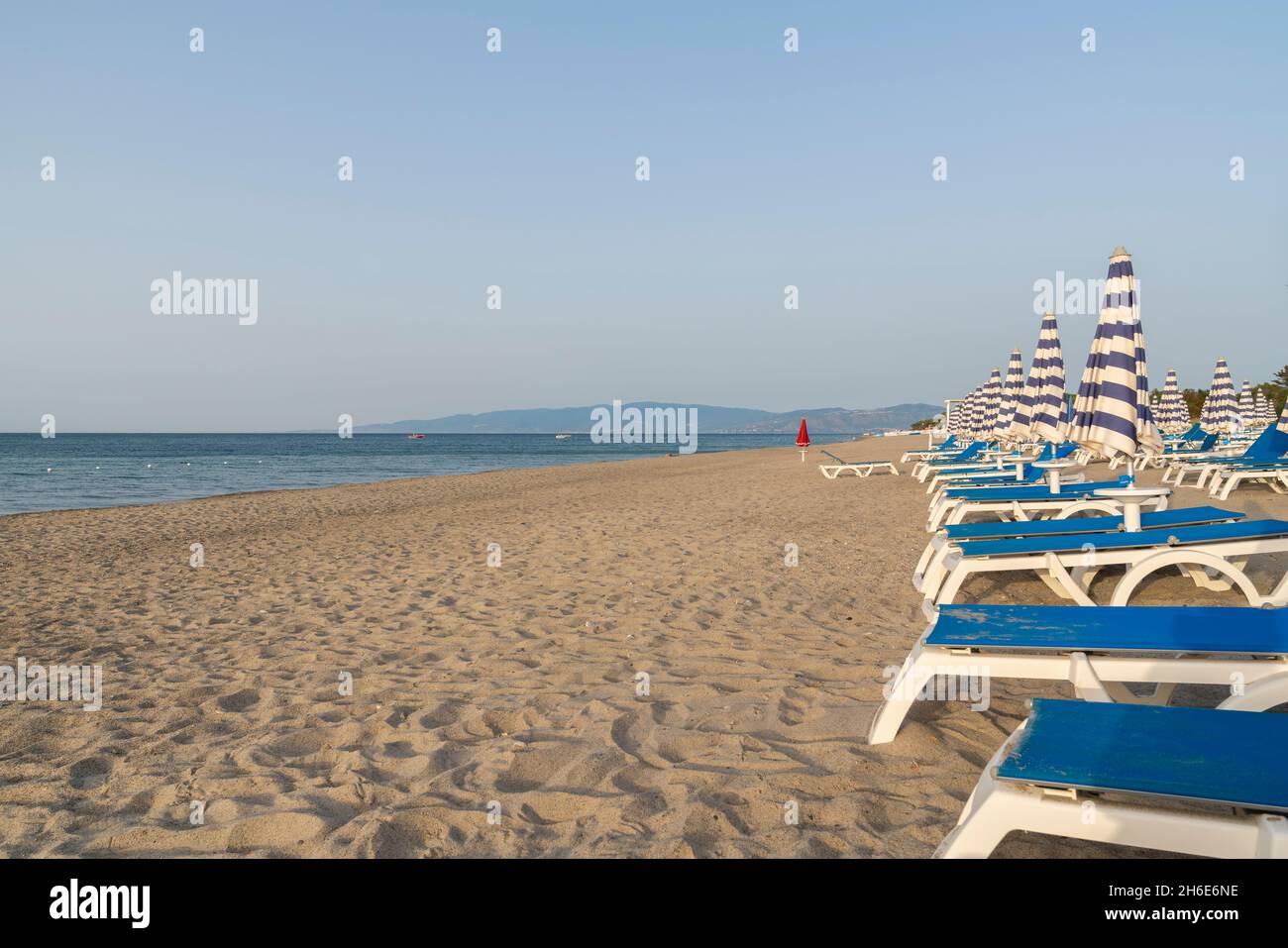 Blue and white umbrella and beach chairs at the beach in front of blue ...