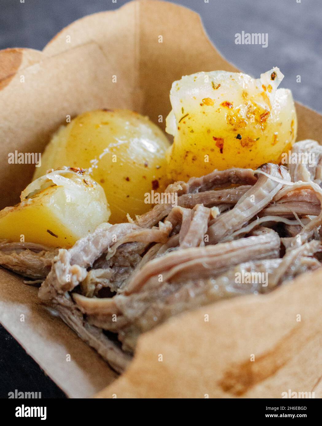 a cardboard plate with roasted and seasoned potatos and shredded rib ...
