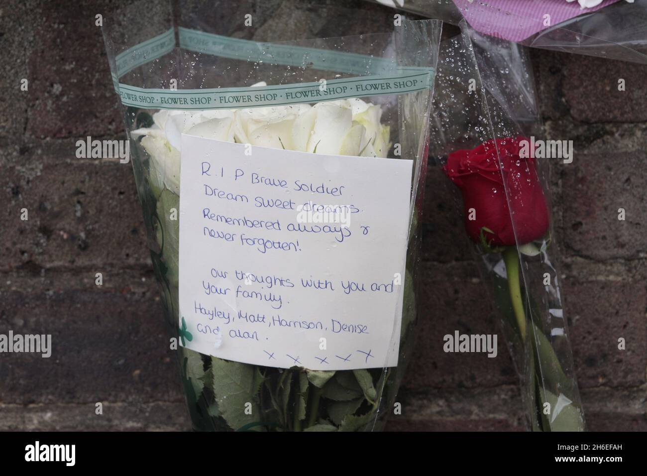 A man and his son place a rose inside a pair of soldiers boots left at ...