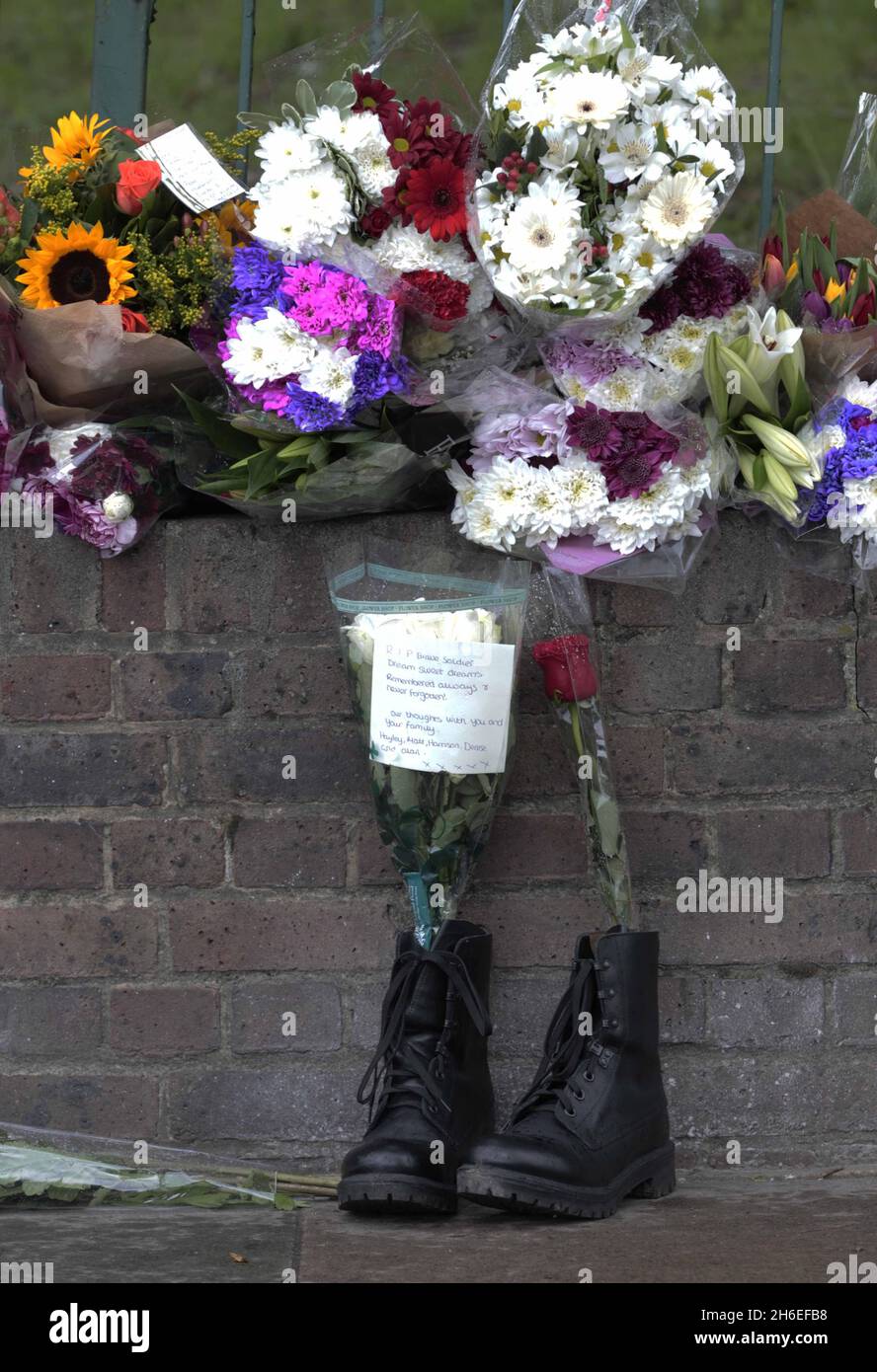 A man and his son place a rose inside a pair of soldiers boots left at ...