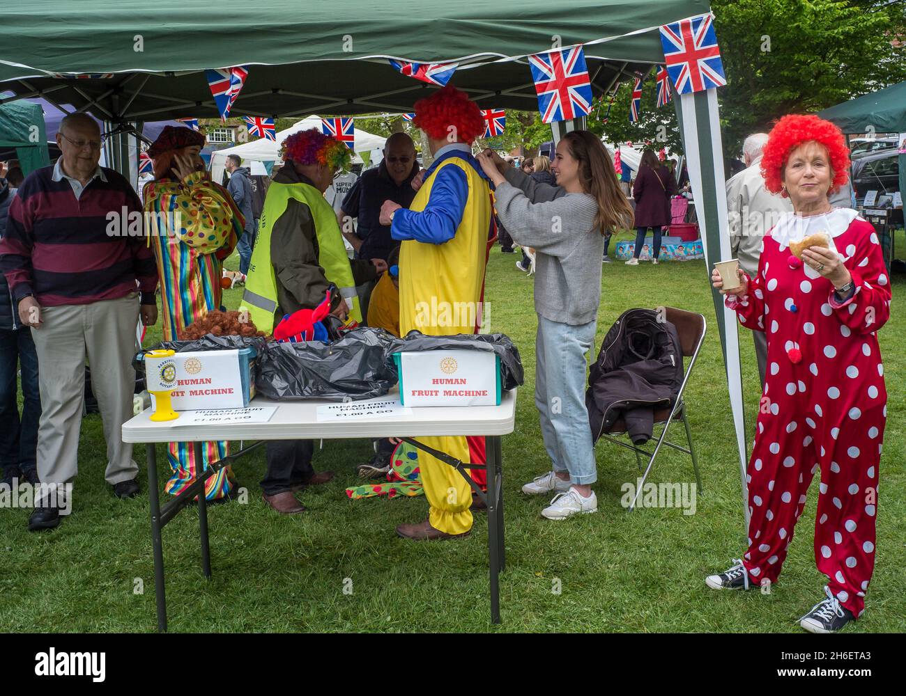 A clown enjoys a burger at the Chigwell May fair in Essex on a damp ...