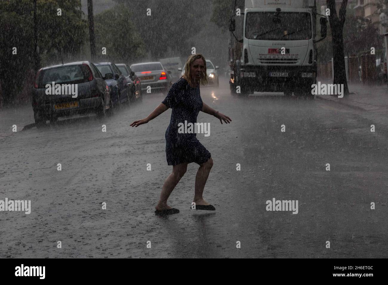 A woman gets caught in heavy rain in East London this afternoon Stock ...