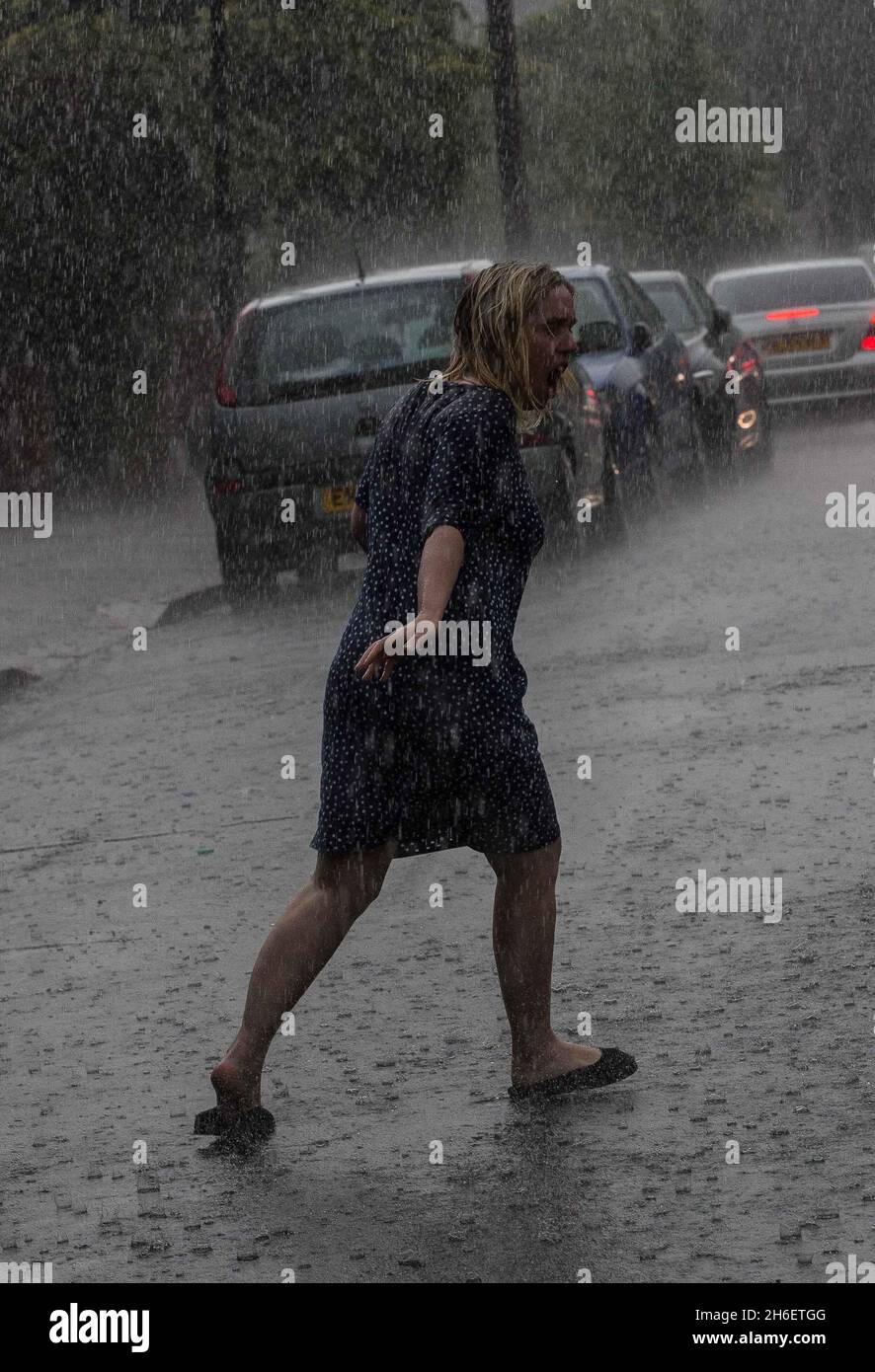 A woman gets caught in heavy rain in East London this afternoon Stock ...