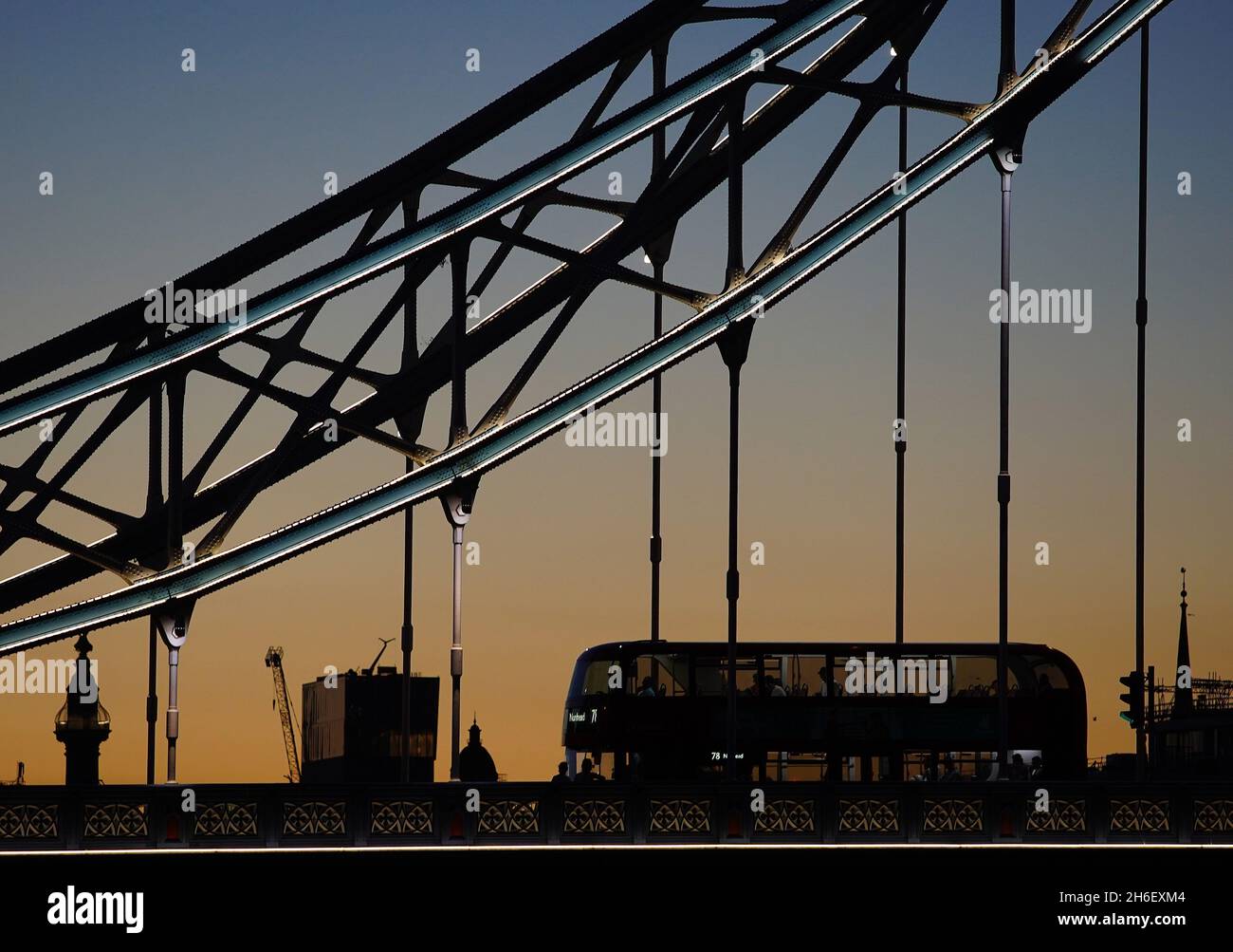 A London bus crosses Tower bridge as the sun sets across the capital ...