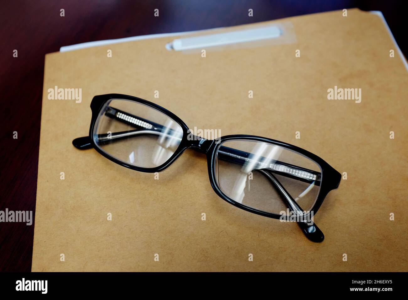 Black glasses on top of a work folder or file on a desk school or ...