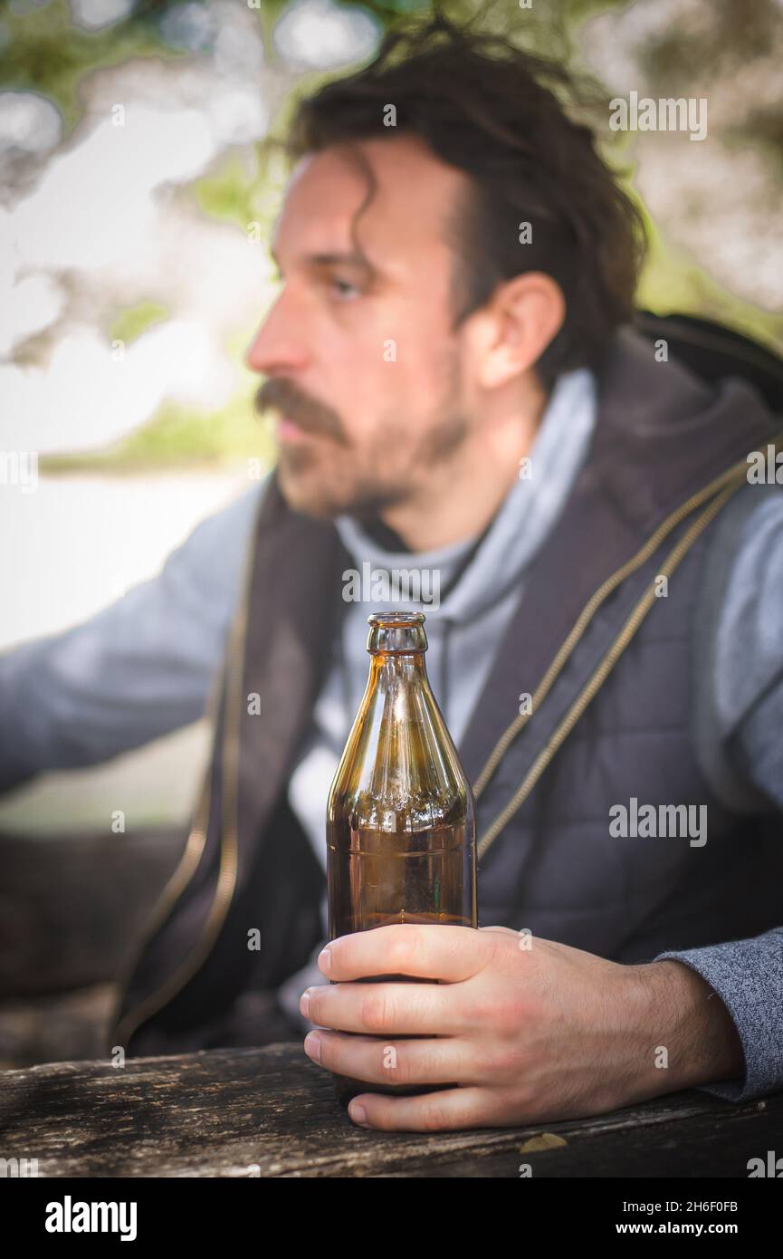 Lonely man drinks beer from bottle alone and thinks about the meaning ...