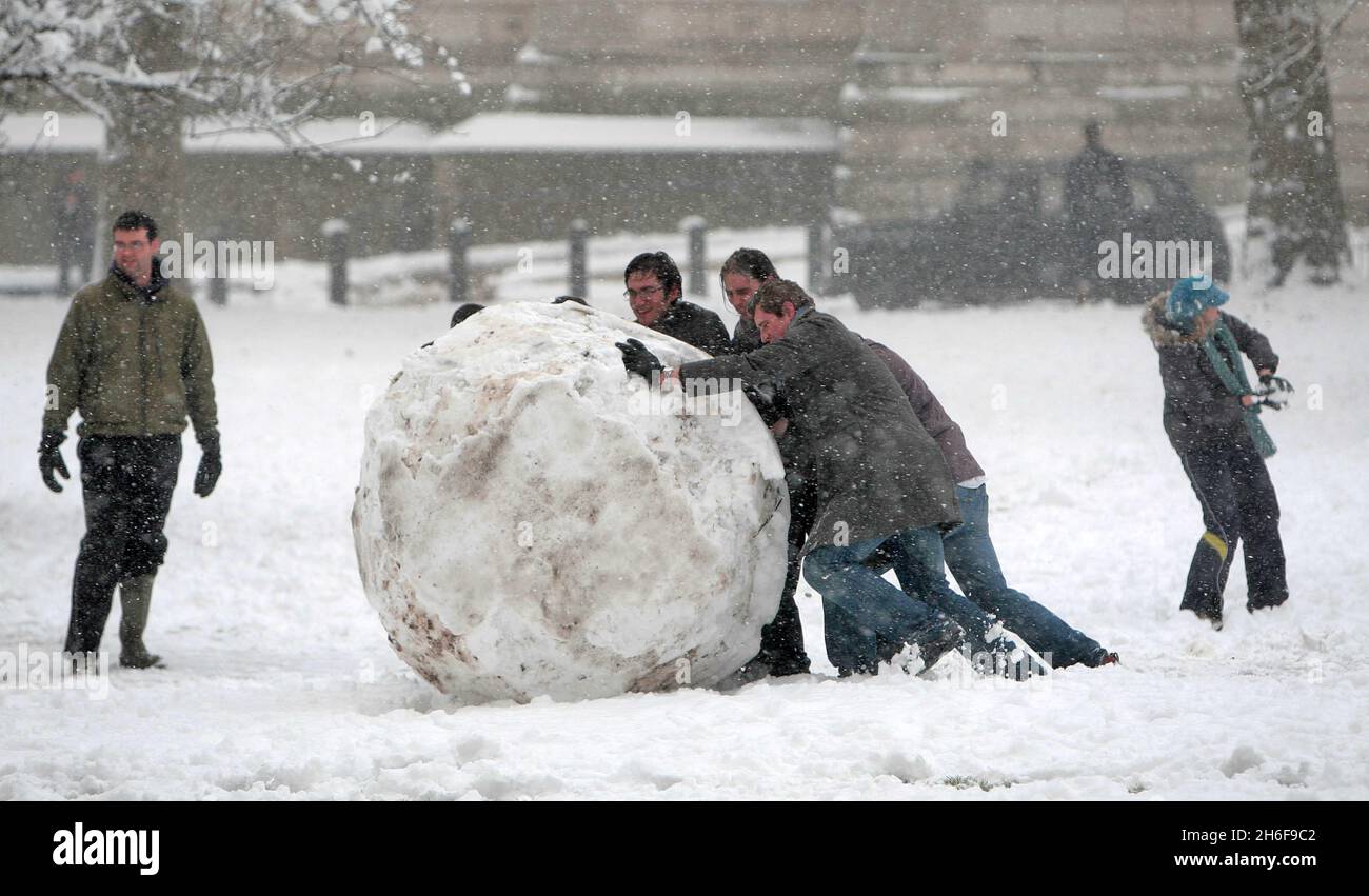 A group of people push a giant snowball in St James Park, central ...