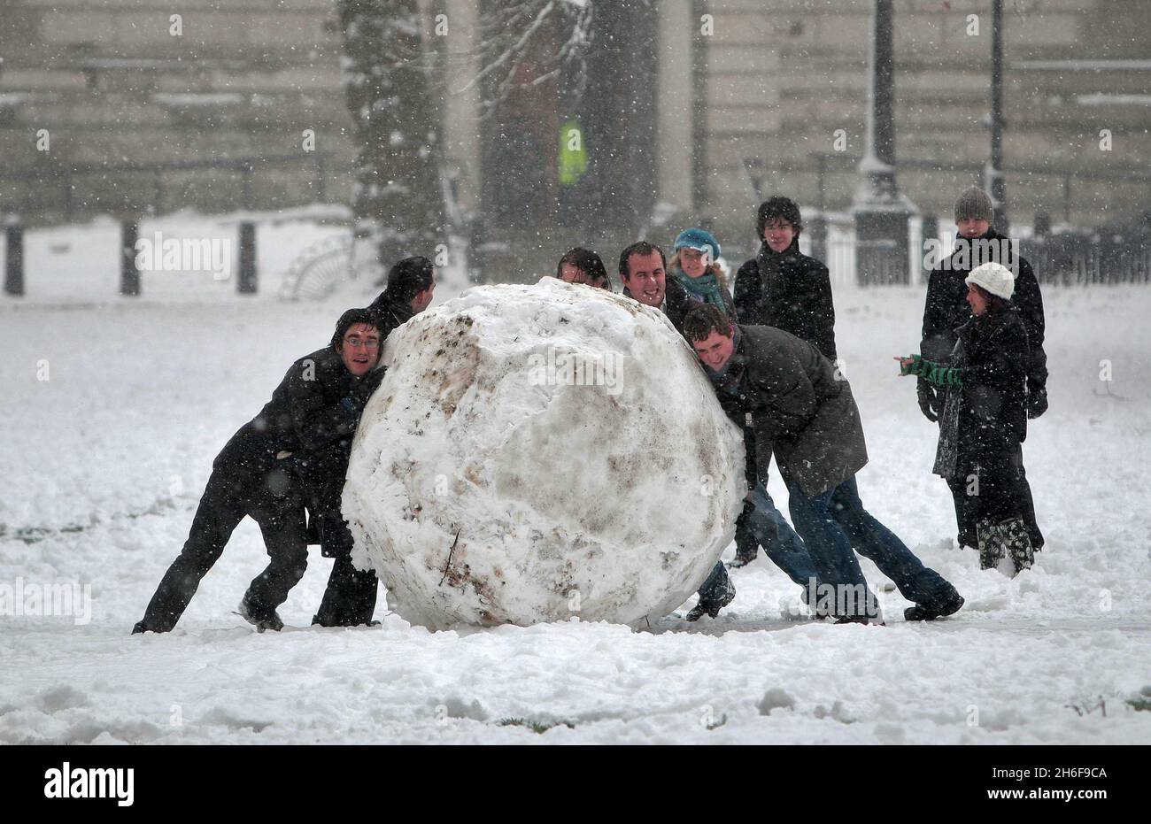 A group of people push a giant snowball in St James Park, central ...