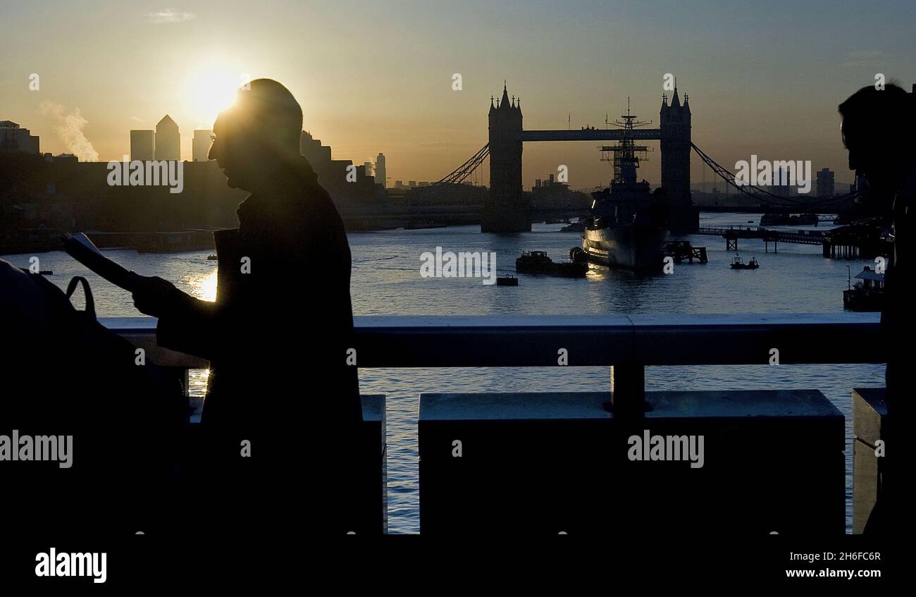 City workers make their way across London bridge as the sun rises ...