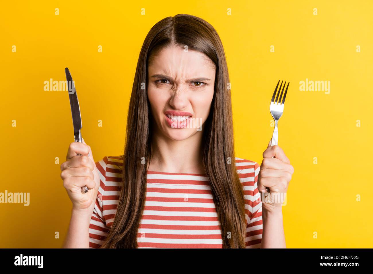 Portrait of attractive angry girl holding cutlery fast food meal snack ...