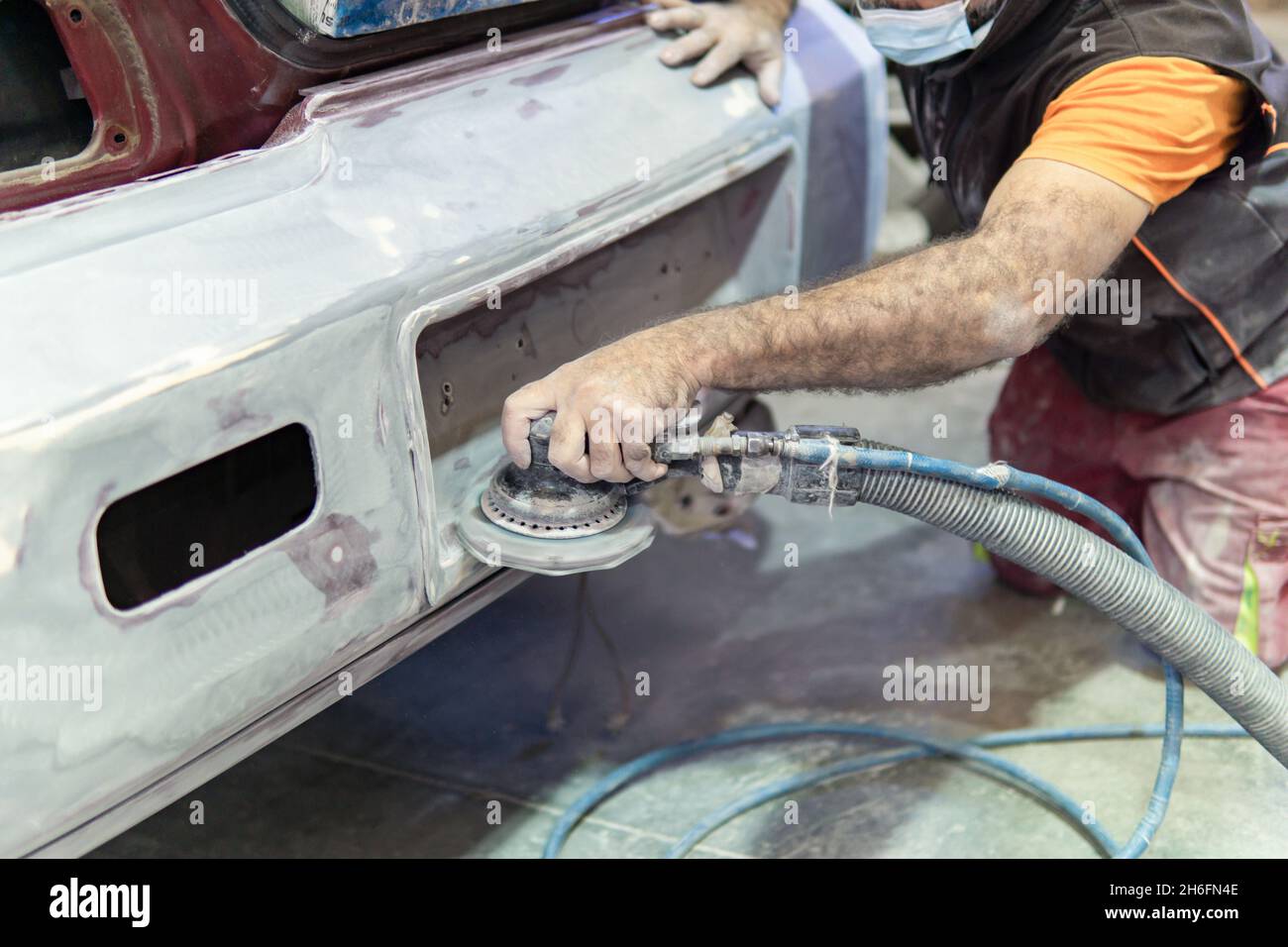 Auto mechanic sanding a part of a car in a garage. Preparing for Stock ...