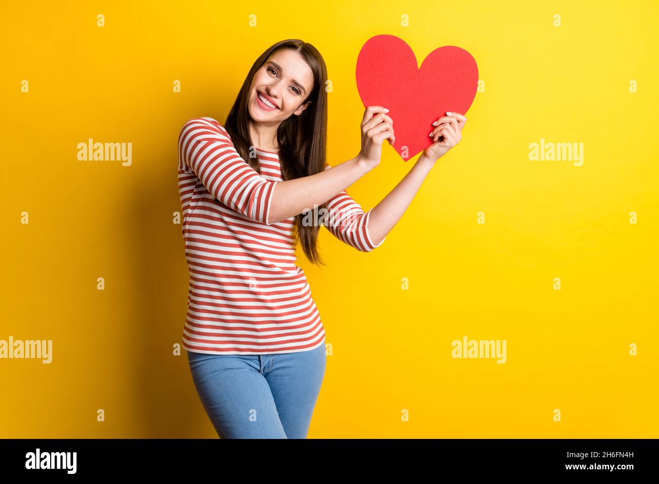 Portrait of attractive cheerful girl holding big heart card affection ...