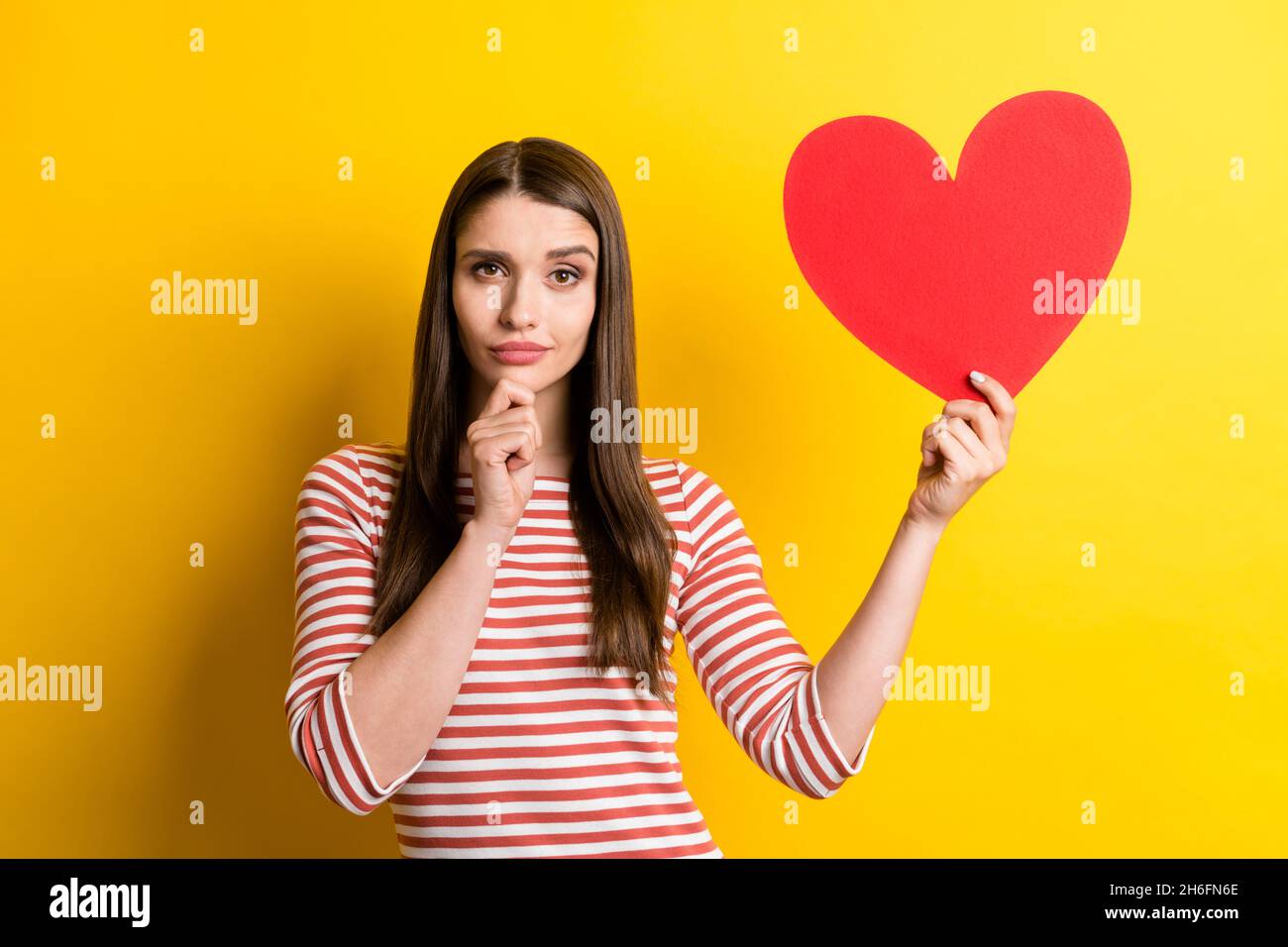 Portrait of attractive doubtful girl holding heart card overthinking ...