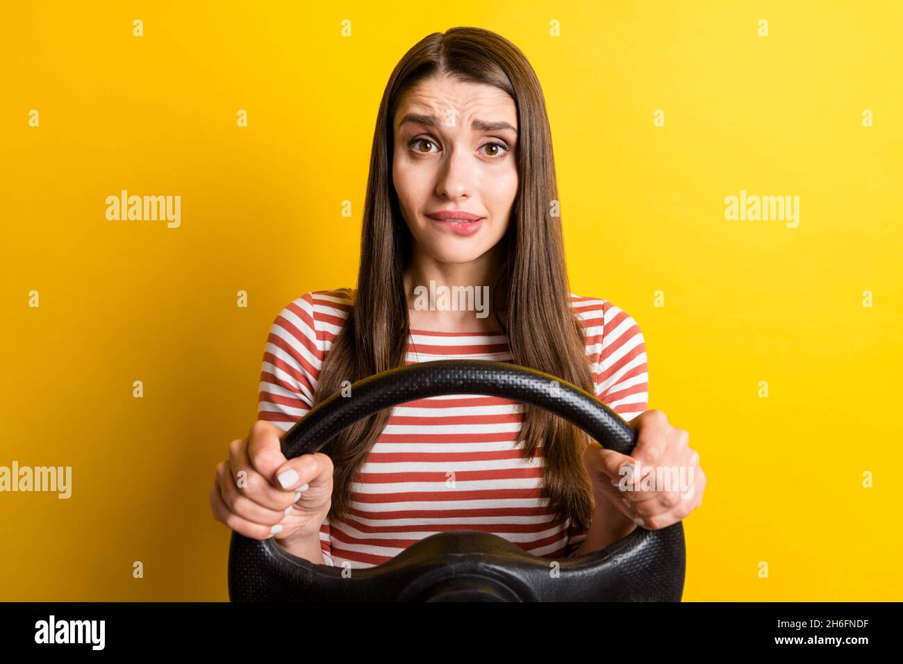 Portrait of attractive confused girl holding steering wheel driving ...