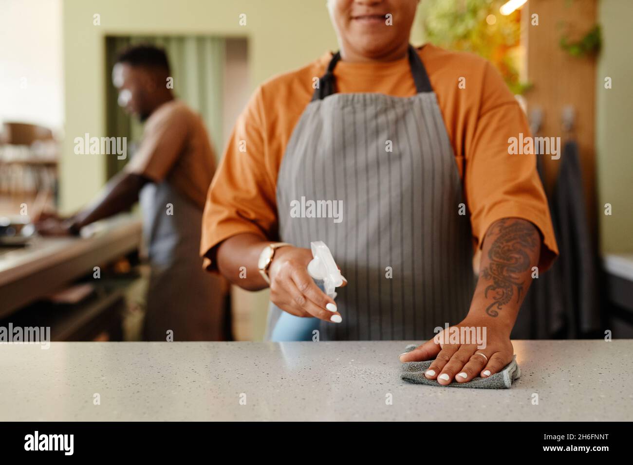 Unrecognizable young African American woman wiping off dust from cafe ...