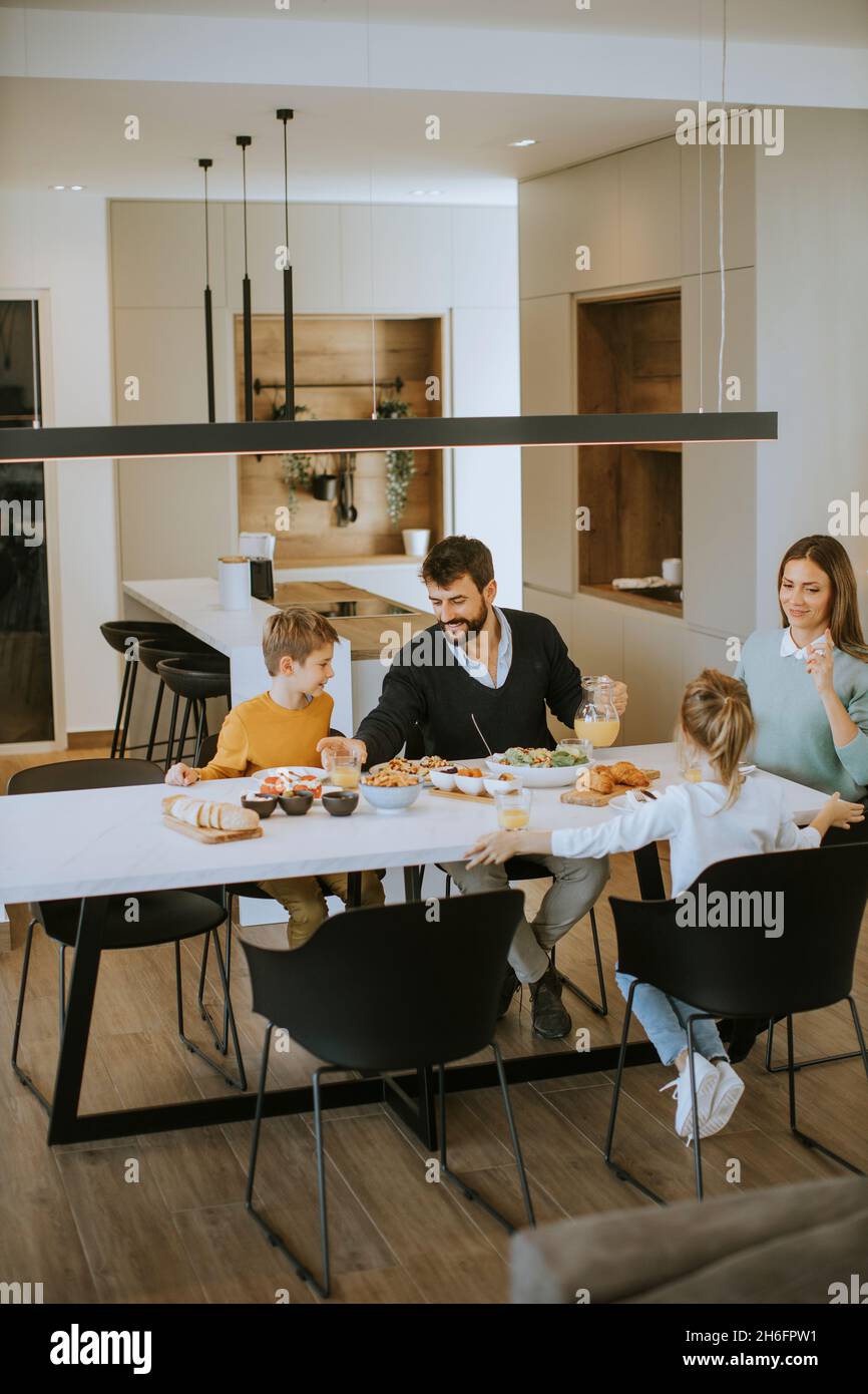 Young happy family talking while having lunch at dining table at ...