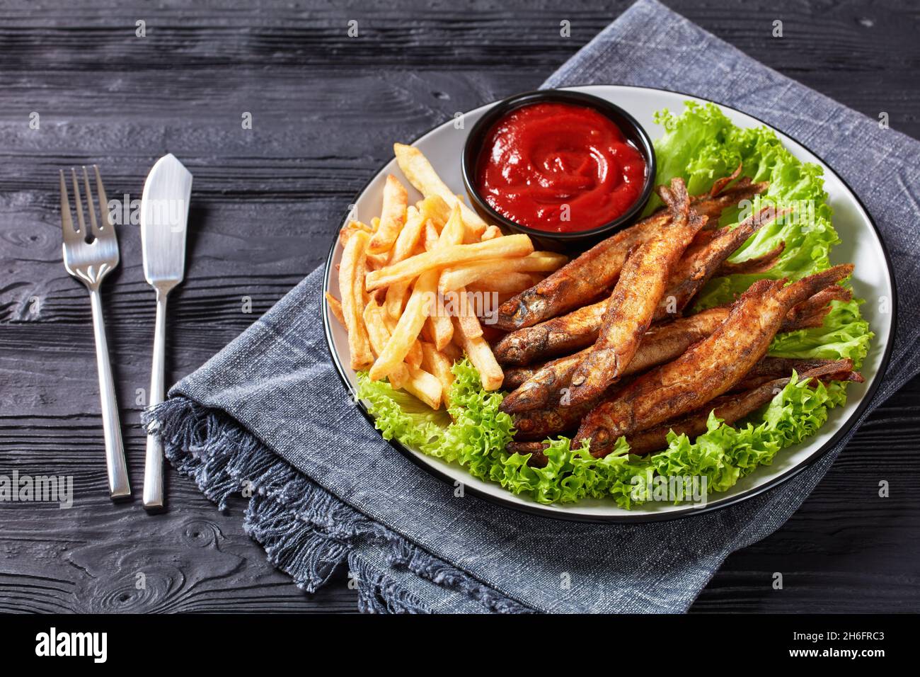 crispy fried capelin fish with fresh lettuce, french fries and tomato ...