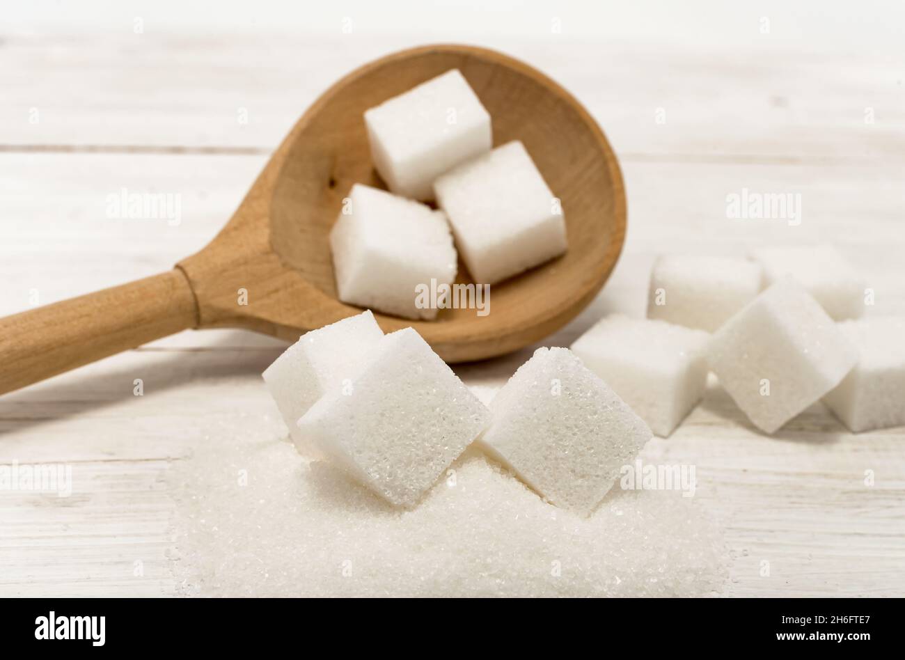 Refined sugar. Sugar lumps are scattered on a wooden surface, table and ...
