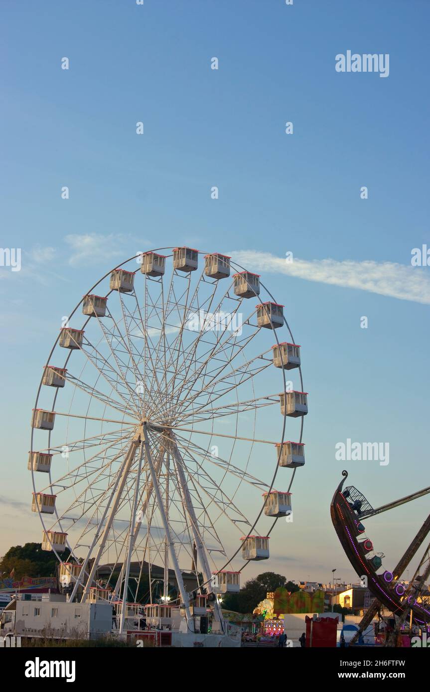 Vertical photograph of a fairground ferris wheel and the bow of a ship ...