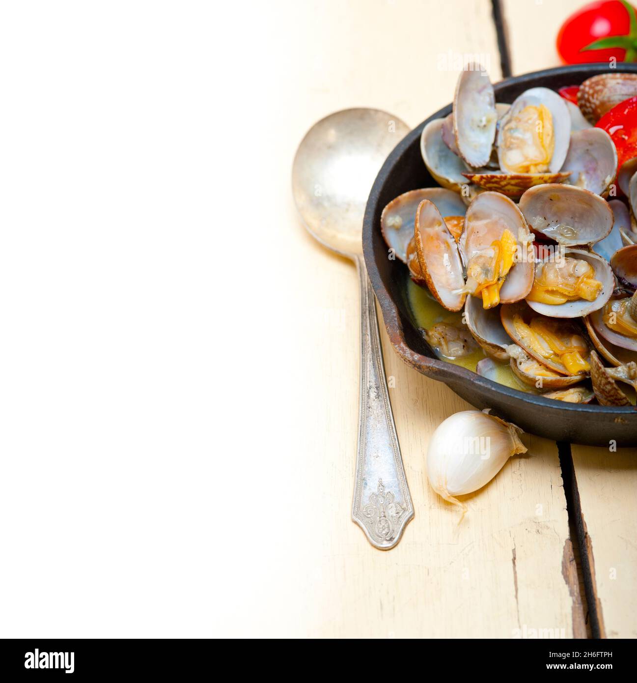 fresh clams stewed on an iron skillet over wite rustic wood table Stock ...