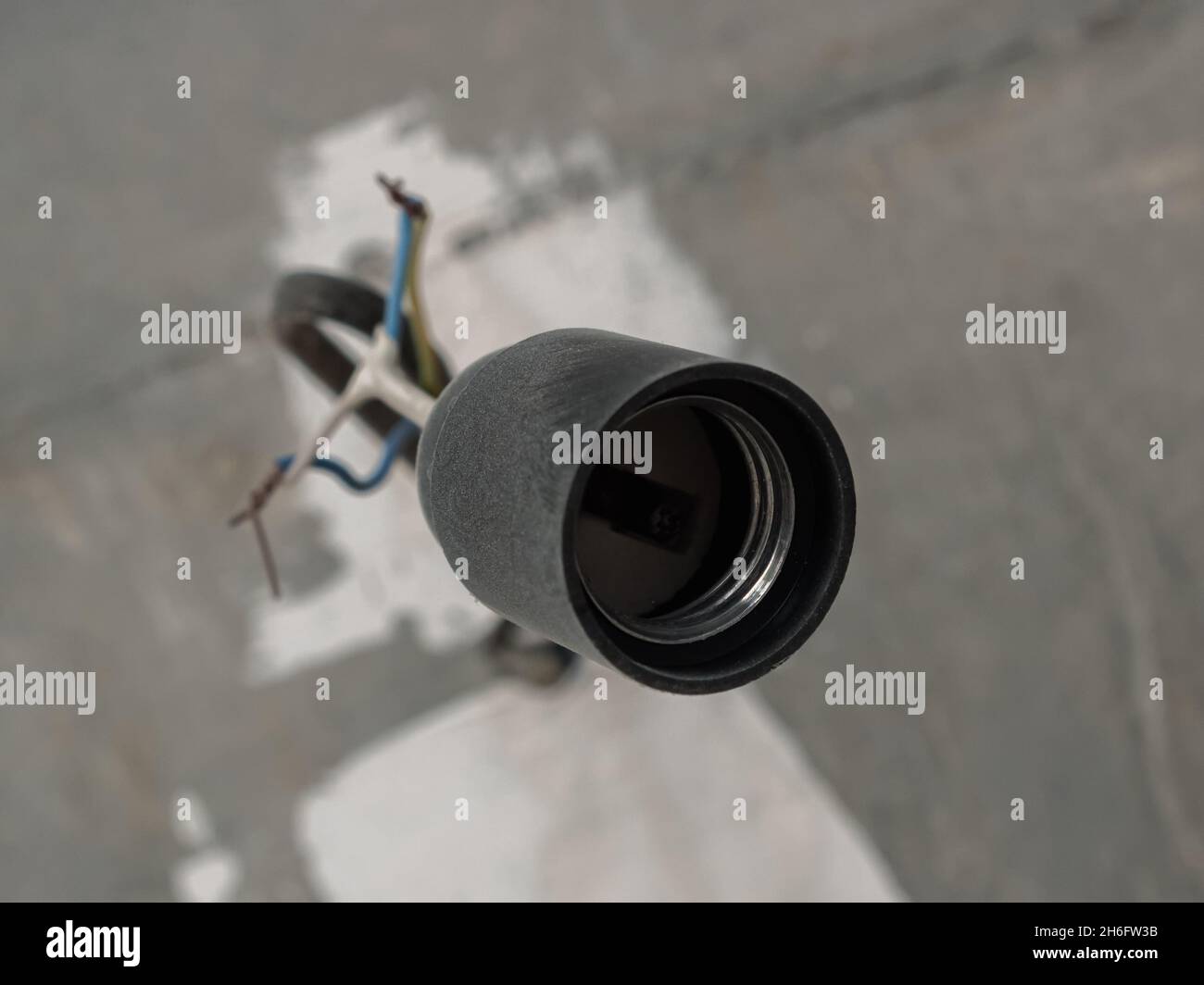 A black plastic empty lamp socket hangs from the ceiling. Close-up. The ...