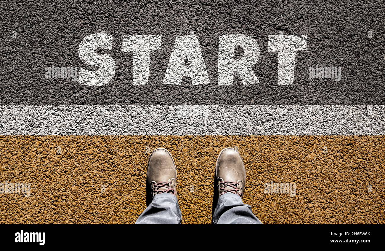The word Start on the asphalt in front of your feet in boots. View from ...
