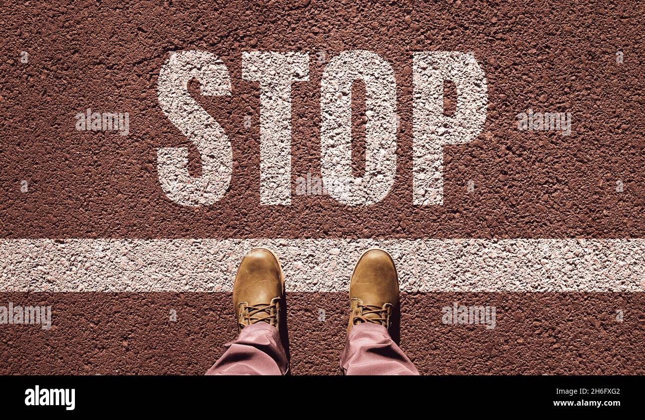 The word Stop in front of your feet in boots. View from above ...