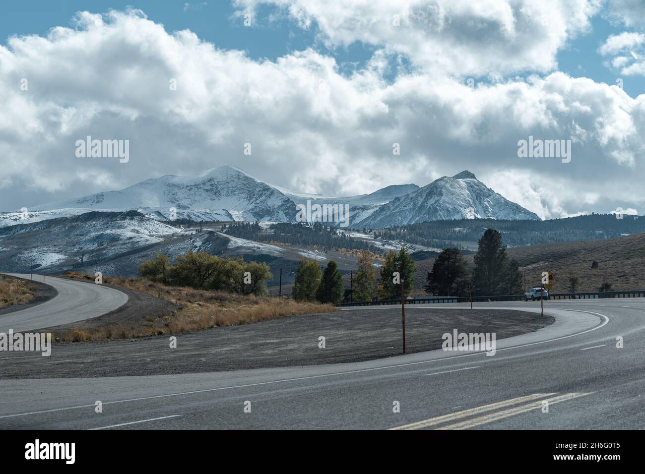 Mesmerizing view of a curvy road with snowy mountains in the background ...