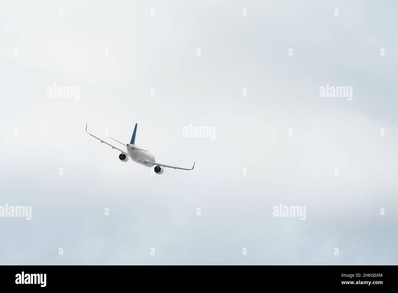 Rear view of a white passenger plane in close-up against a gray sky ...