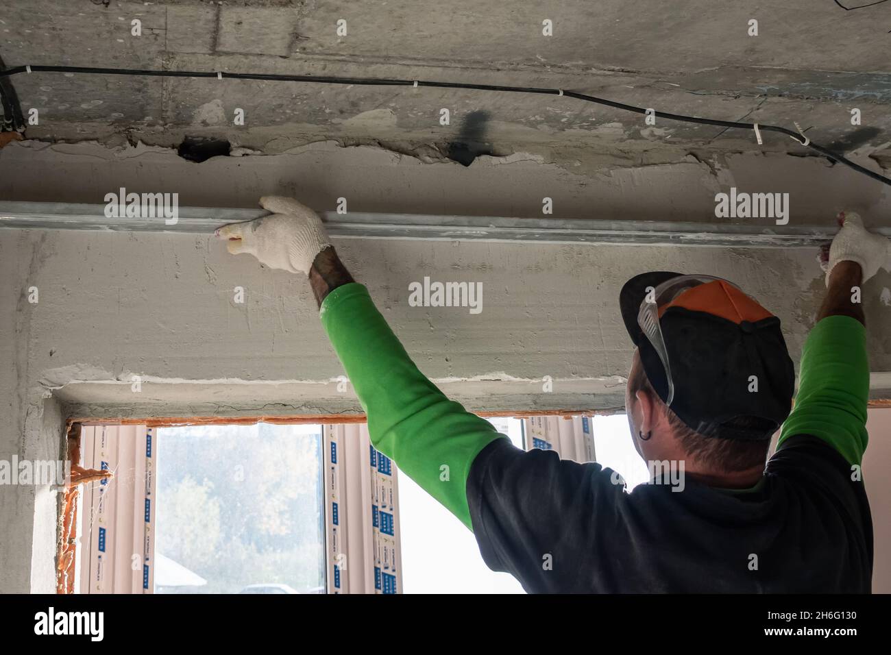 A construction worker plastering a wall with an aluminum rule. Back ...