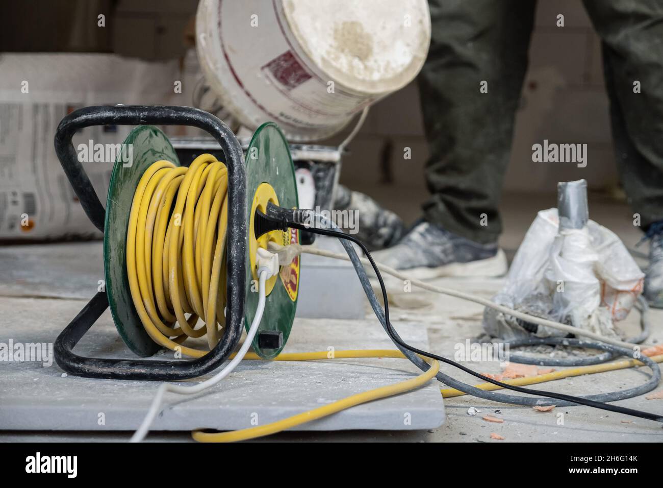 Yellow electric extension cord on a green spool. Four plugs are plugged ...