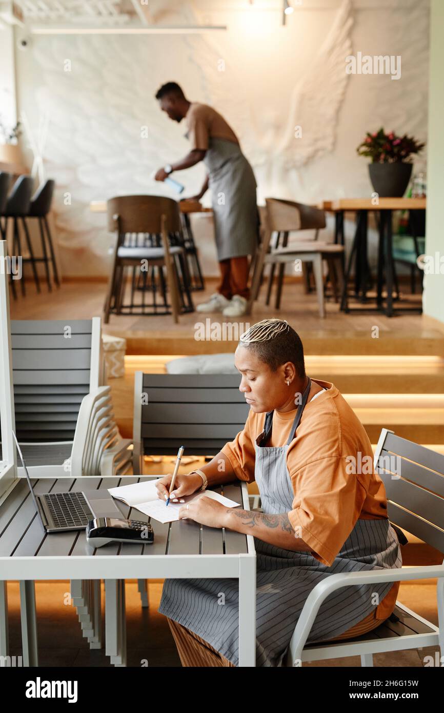 Side view shot of young man and woman working in modern cafe preparing ...