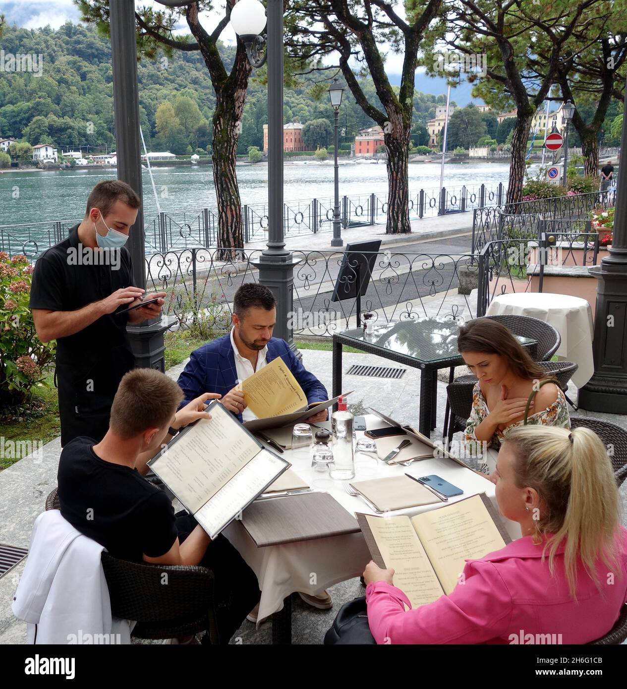 Restaurant waiter taking order from diners at Lenno on Lake Como, Italy ...