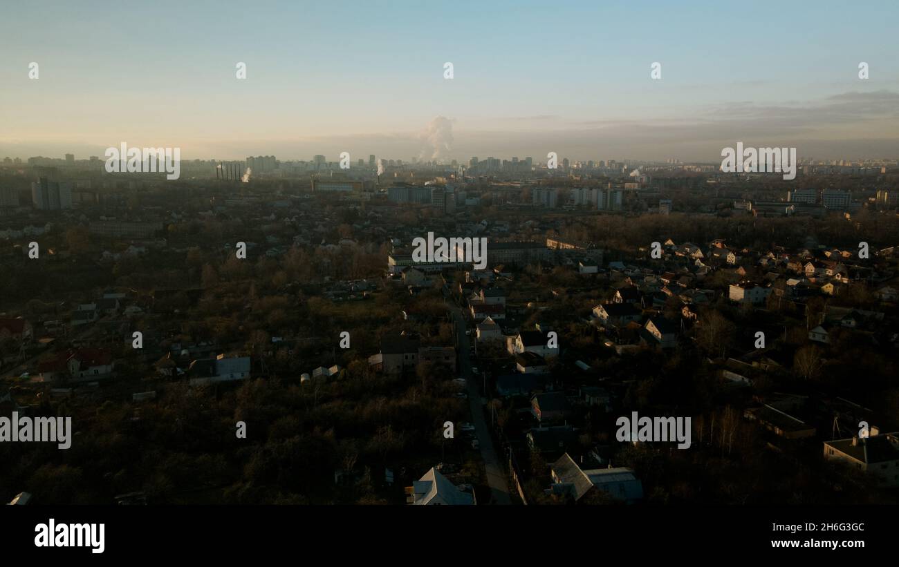 The suburb is backlit by the setting sun. Houses, a park area and a ...