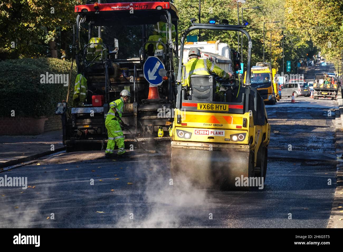 Workers using road roller in street resurfacing works in London England ...